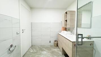 Um banheiro moderno com box de vidro, piso de mármore e toucador de madeira com espelho.