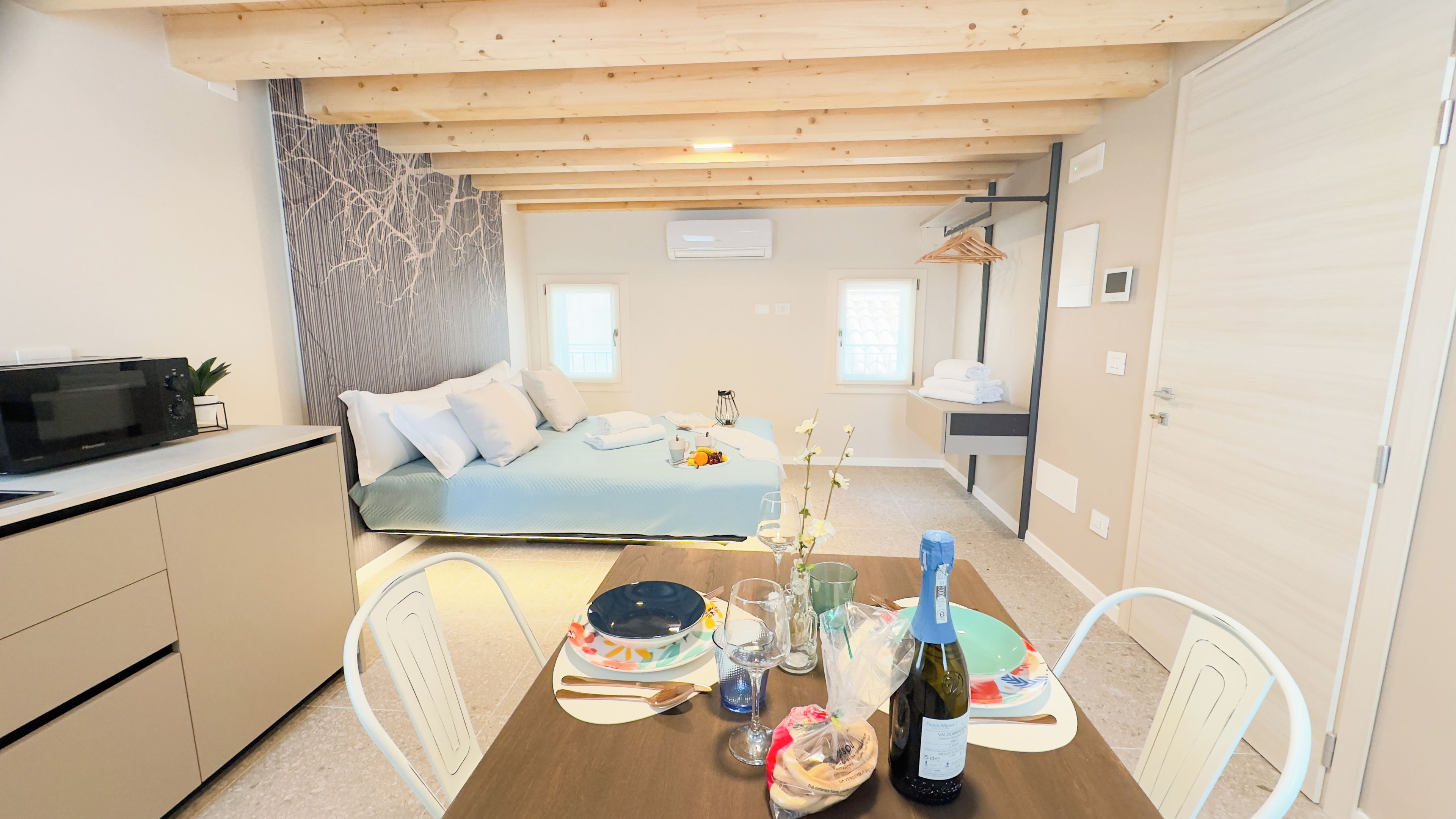 Quarto compacto com cama, mesa de jantar e cozinha compacta.