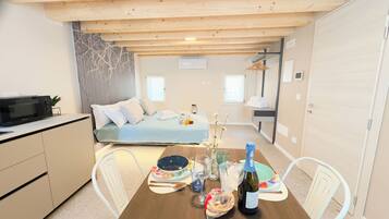 Quarto compacto com cama, mesa de jantar e cozinha compacta.