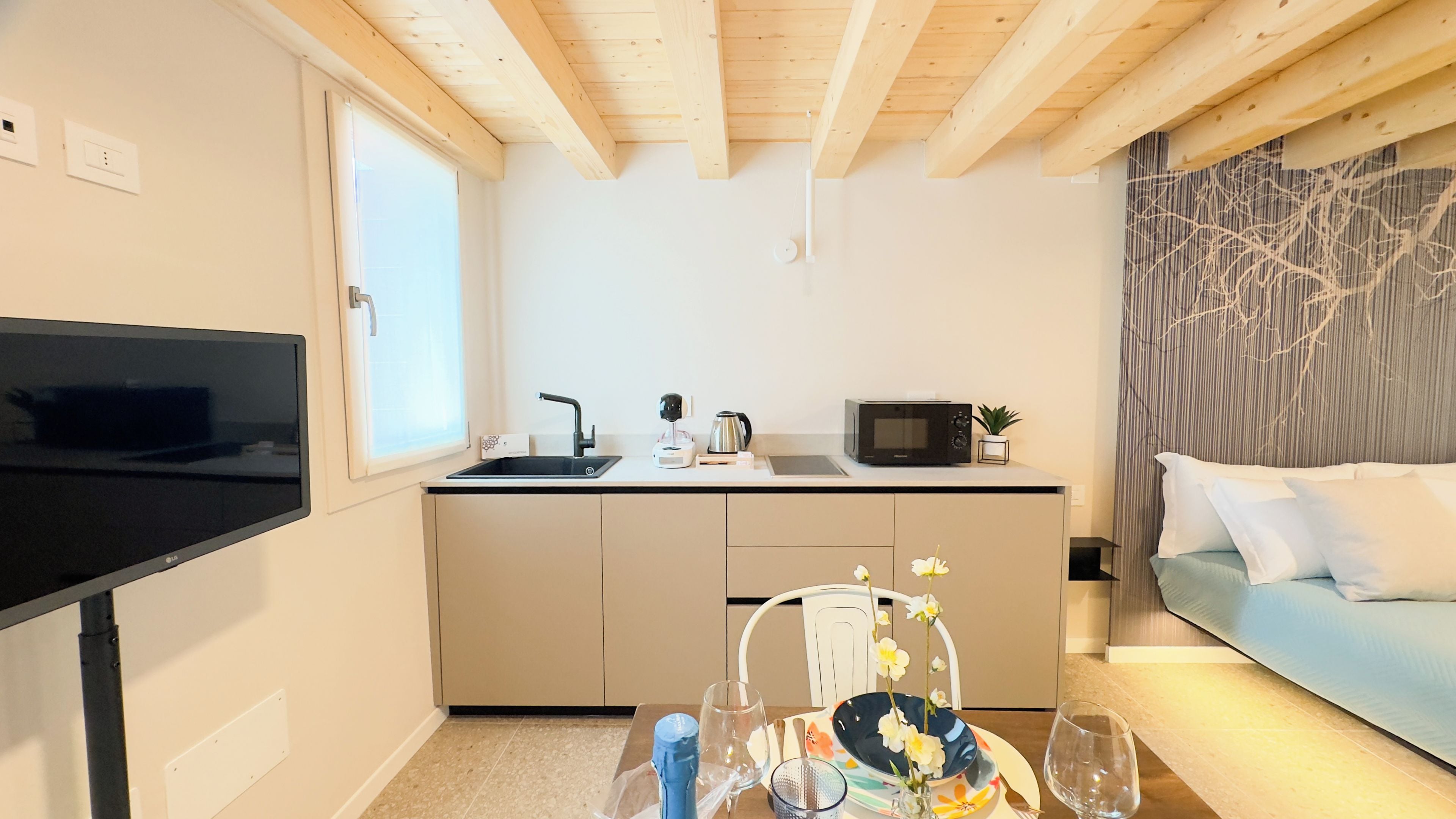 Espaço compacto com cozinha compacta, televisão de tela plana, sofá e área de jantar com mesa posta para dois.