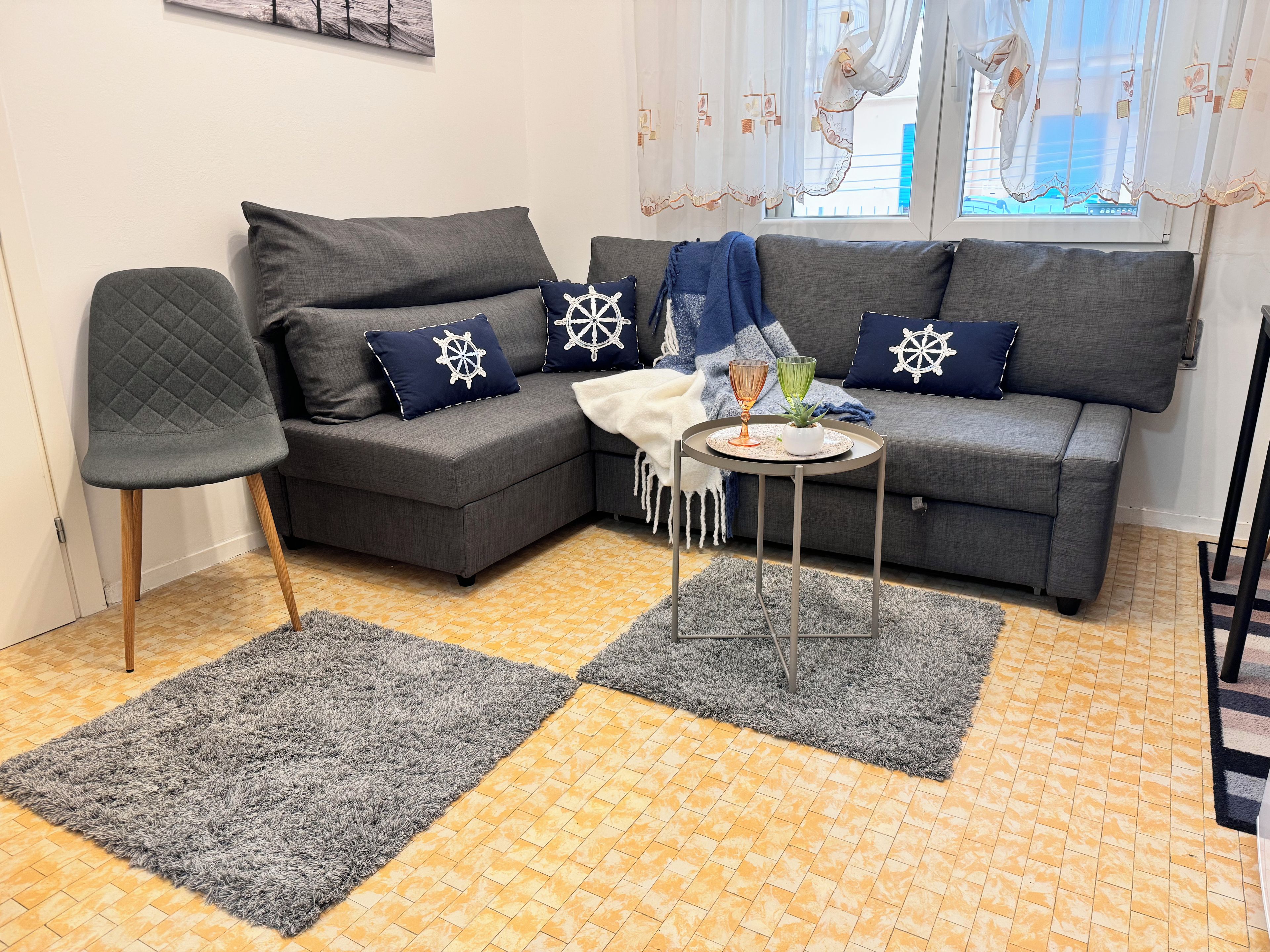 Uma sala de estar moderna com um sofá cinzento, poltronas a combinar e uma mesinha redonda com objetos decorativos.