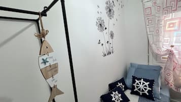 Quarto com cama, almofadas, um adorno na parede e um objeto pendurado.