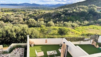 Terraço no telhado com vista para uma paisagem exuberante, paredes de pedra e uma pequena área de estar.