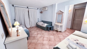 Quarto de hotel com cama, escrivaninha, cadeira, espelho e guarda-roupa.