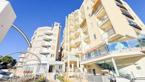 Um edifício residencial com vários andares, varandas, espaço comercial no térreo e entrada visível.