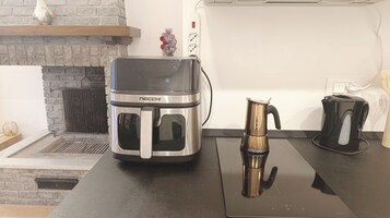 Uma cozinha com uma cafeteira moderna, uma chaleira e uma torradeira na bancada.