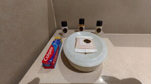 Uma pia de banheiro com uma barra de sabão, uma caixa de creme dental Colgate e três frascos de loção corporal.