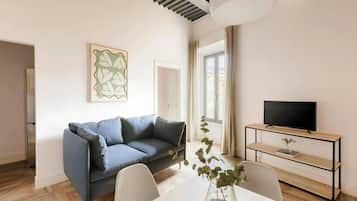 Uma sala de estar moderna com um sofá, uma mesa de jantar e uma televisão sobre um suporte de madeira.