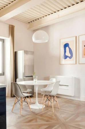 Uma área de jantar moderna com uma mesa redonda, duas cadeiras e uma luminária pendente.