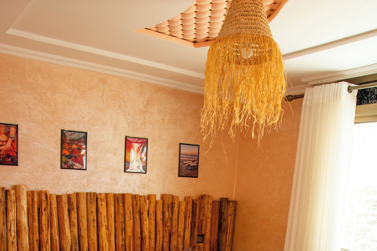 Quarto com cama de madeira, cabeceira trançada e luminária pendente.