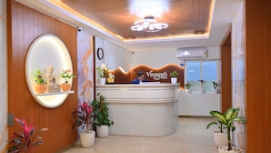 Bancada de recepção com relógio, plantas em vasos e placa indicativa para Vinsara Inns.