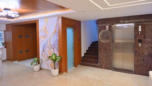 Um lobby moderno com parede de mármore, portas de madeira, escada e elevador.