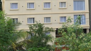 Um edifício de vários andares com uma placa indicando 'Vinsara Inns' e várias janelas com cortinas.