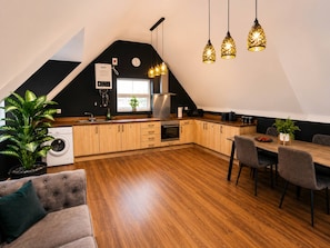 Cozinha moderna com armários de madeira, forno embutido e área de jantar com mesa e cadeiras.