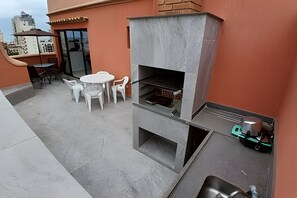 Um pátio externo com churrasqueira, área de estar e uma pequena mesa.