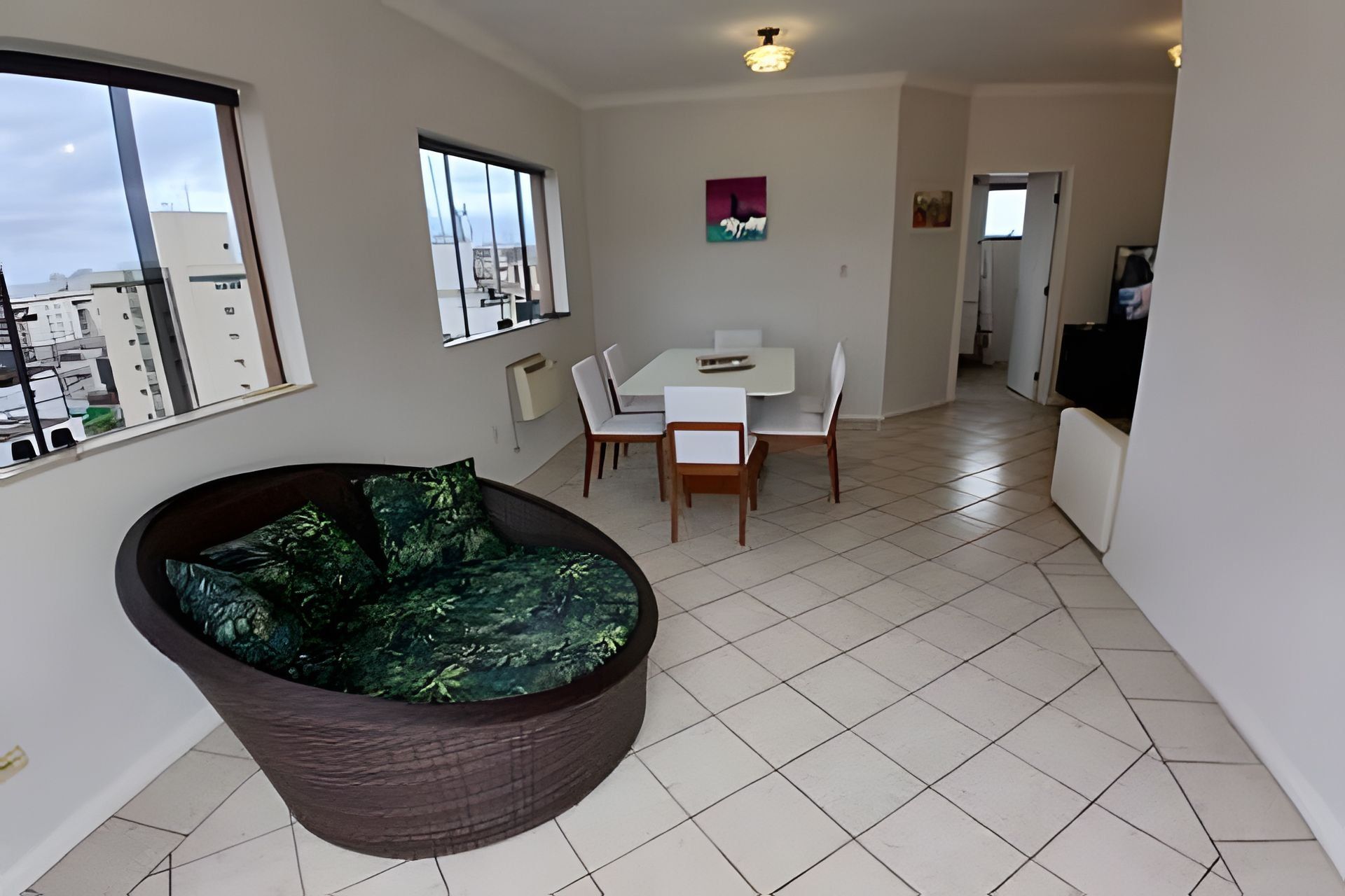 Uma sala de estar moderna com uma janela grande, uma área de jantar com mesa e cadeiras, e uma cozinha.