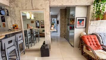 Uma cozinha moderna com área de bar, espaço de jantar com cadeiras, um sofá e um espelho refletindo o ambiente.