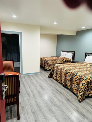 Quarto de hotel com duas camas, uma cadeira de madeira e uma porta que dá para o banheiro.