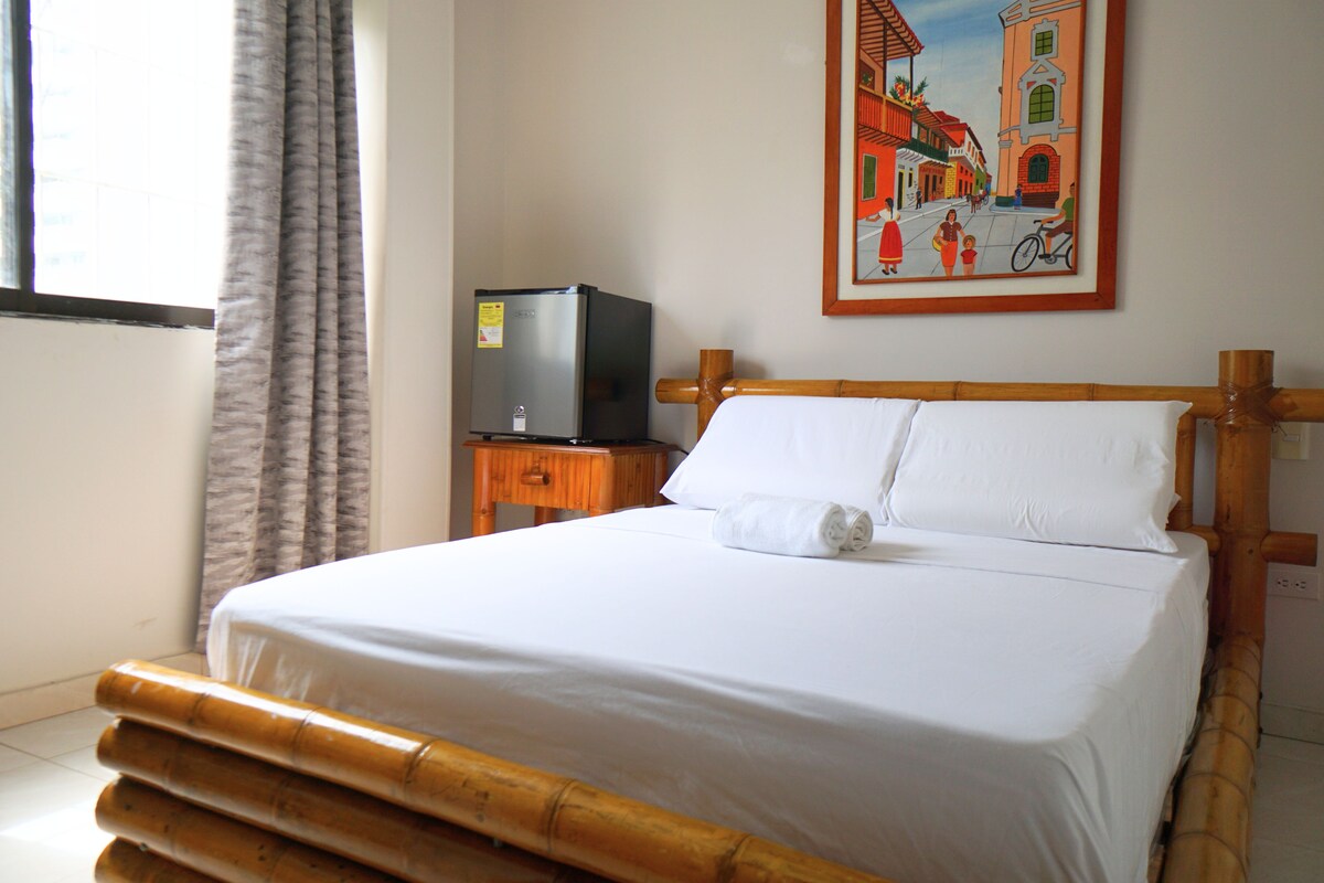 Quarto de hotel com uma cama, televisão e um quadro na parede.