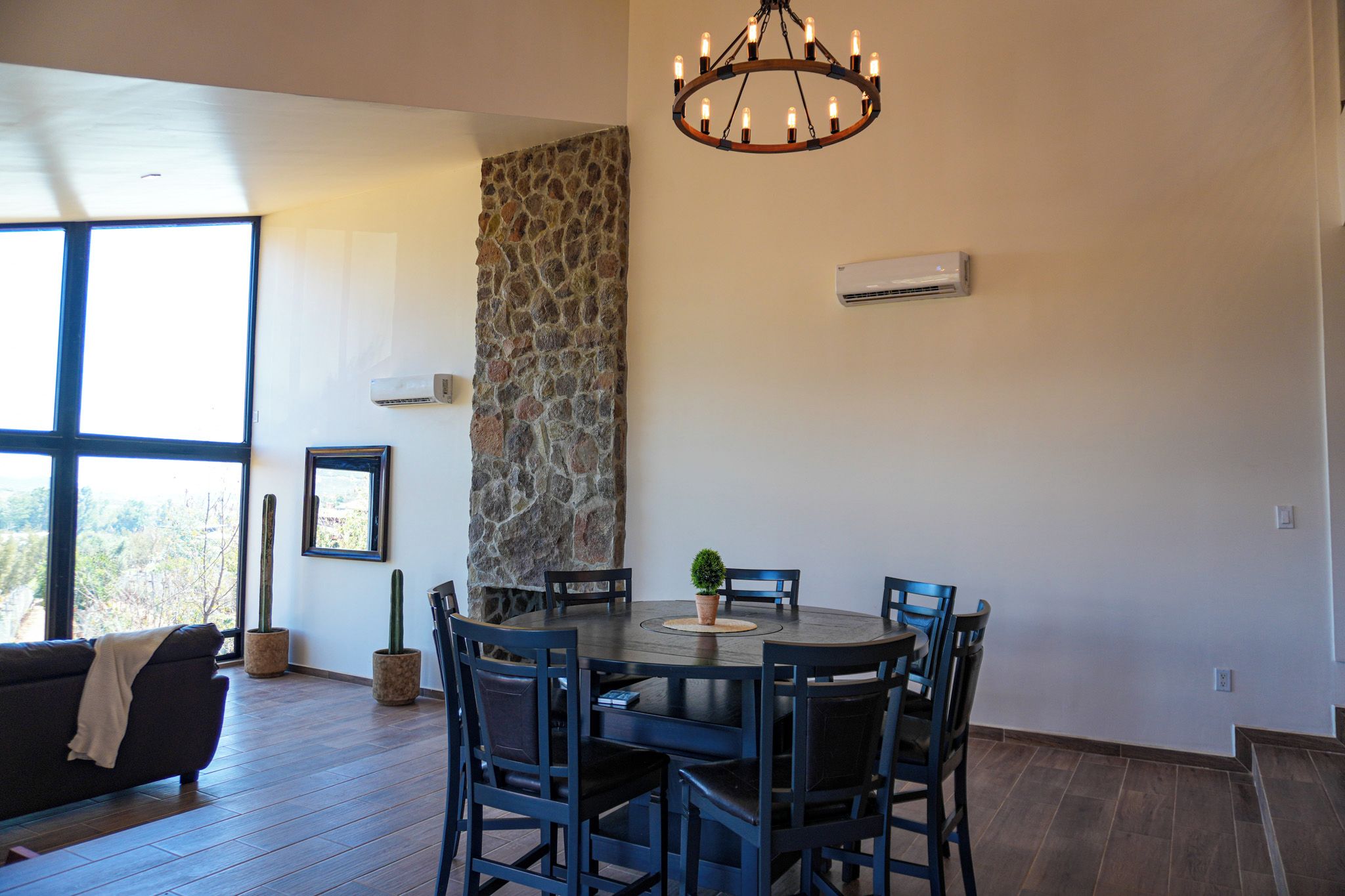 Uma sala de jantar com parede de pedra, um candelabro e uma mesa com cadeiras.