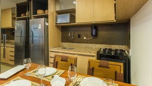 Cozinha moderna com eletrodomésticos embutidos, armários de madeira e uma área de refeições preparada para quatro pessoas.