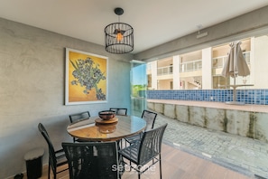 Uma área de refeições com uma mesa redonda, cadeiras pretas e um lustre.