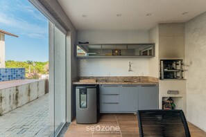Uma cozinha compacta com armários cinzas, forno embutido e lava-louças.
