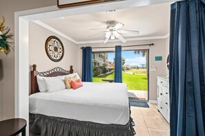 Quarto com cama, ventilador no teto, vista para o exterior e aviso de proibição de fumar.