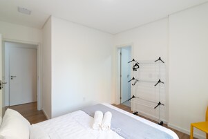 Quarto com cama, porta e porta-toalhas.