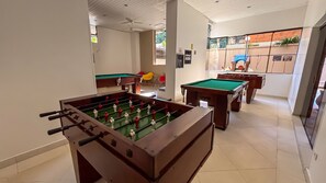 Um quarto com mesa de pebolim, mesa de bilhar e área de recreação infantil.