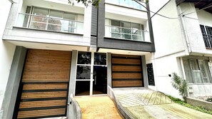 Um edifício moderno com duas grandes portas de garagem, uma pequena entrada e uma escada de concreto que leva à entrada.