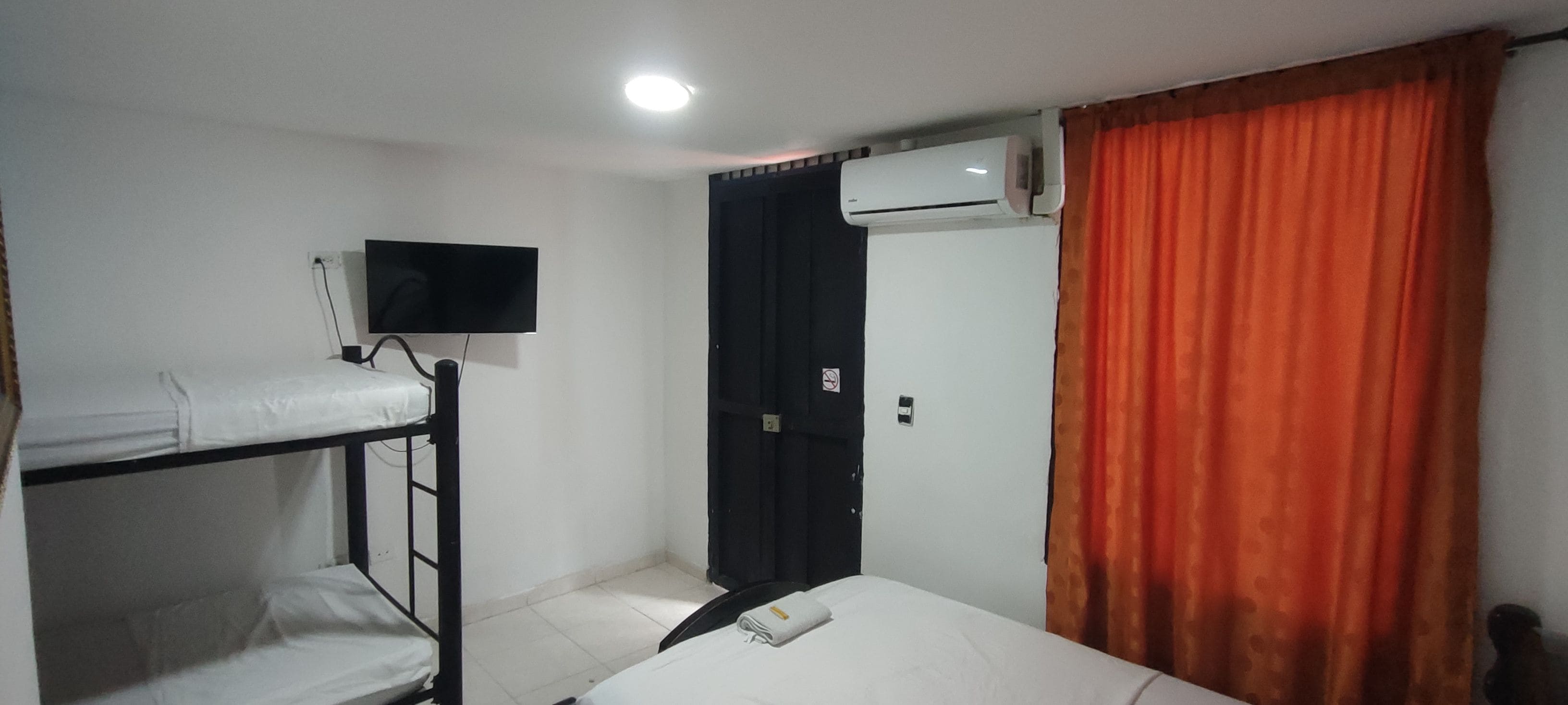 Quarto com beliches, TV de tela plana, ar condicionado e porta com placa de proibido fumar.