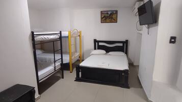 Quarto com beliches, uma cama de solteiro, televisão fixada na parede e um quadro.