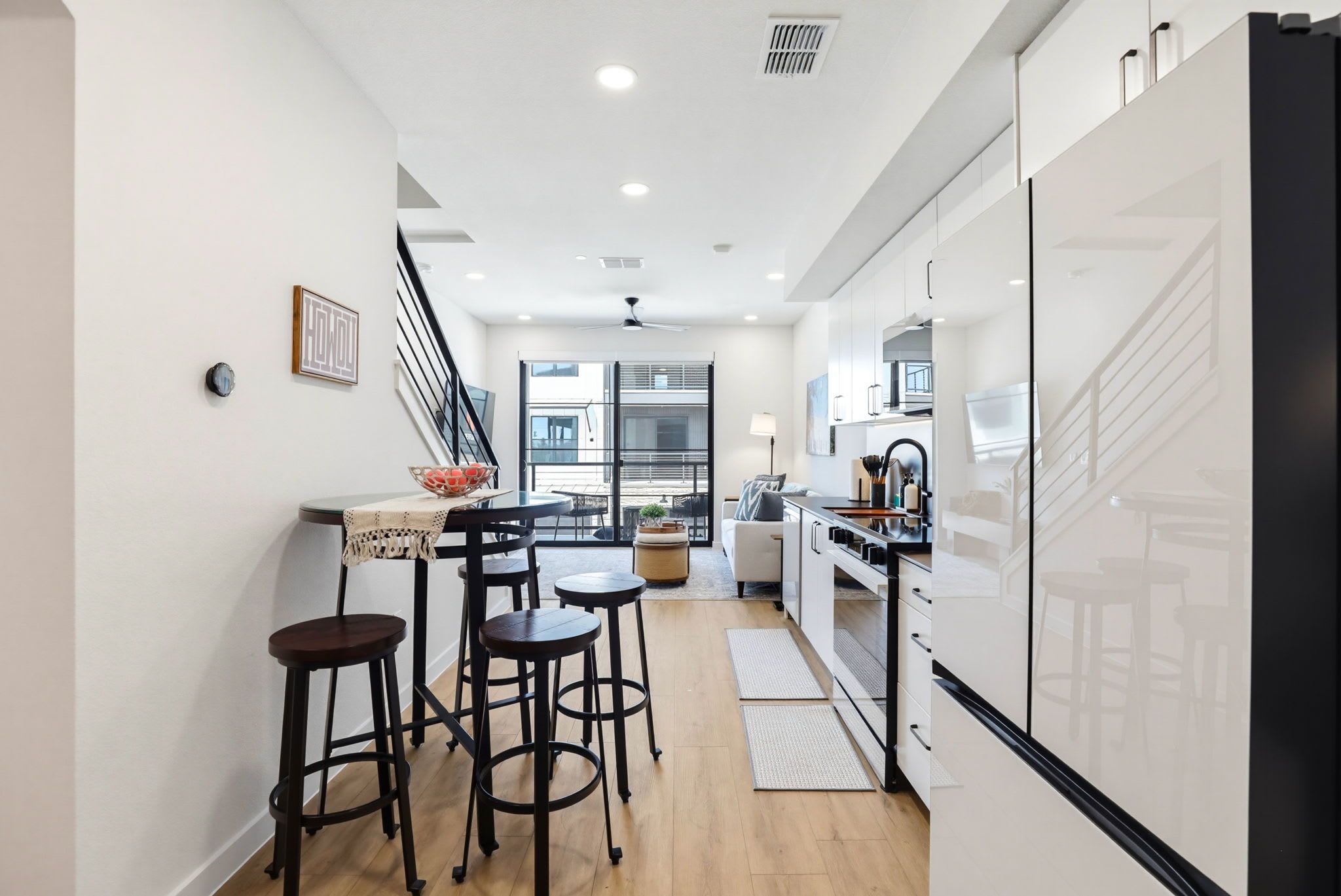 Uma cozinha moderna com área de jantar, escada e vista para o exterior.