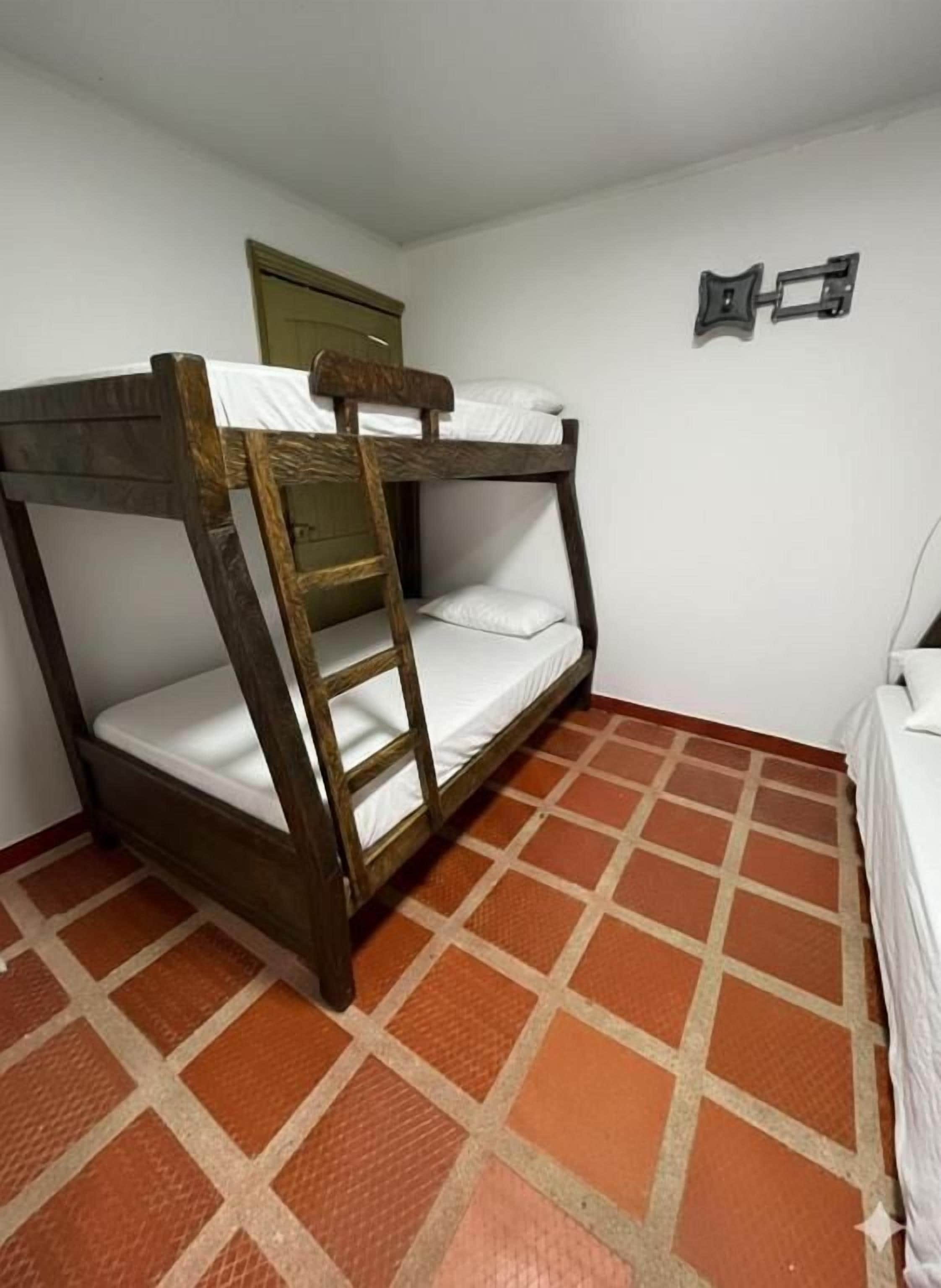 Uma cama beliche em um quarto com piso cerâmico e uma porta ao fundo.