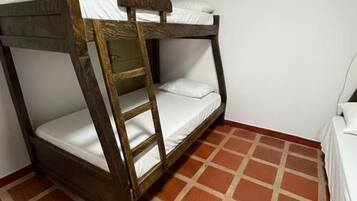 Uma cama beliche em um quarto com piso cerâmico e uma porta ao fundo.