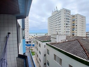 Vista de uma paisagem costeira com edifícios altos, uma praia e céu claro.