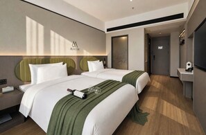 Quarto de hotel com duas camas, um minibar, uma televisão e uma obra de arte na parede.
