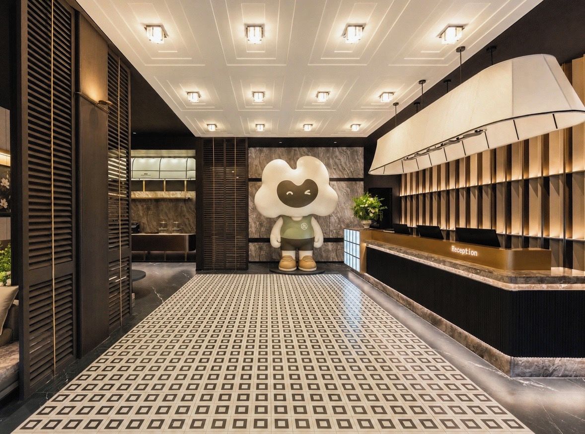 Uma área de recepção de hotel com uma grande decoração de parede estilizada, um balcão de recepção e um piso com padrão.