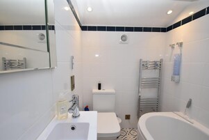 Uma casa de banho moderna com lavatório, sanita e banheira brancos.