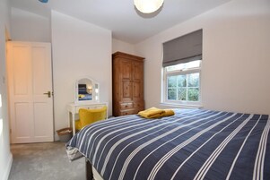 Quarto com cama, cômoda, espelho, janela e porta.