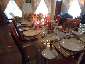 Mesa de jantar posta para quatro pessoas, com pratos, talheres e velas.