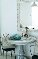 Uma sala de jantar com mesa redonda, cadeiras e espelho emoldurado com detalhes requintados.