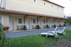 Um edifício com varanda coberta e várias portas, possivelmente um hotel ou pousada.