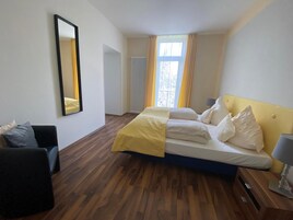 Quarto de hotel com cama, mesa de cabeceira, abajur e espelho na parede.