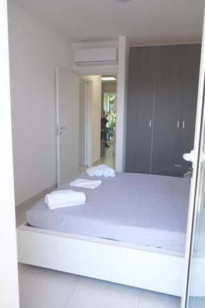 Quarto com cama, guarda-roupa e ar condicionado.