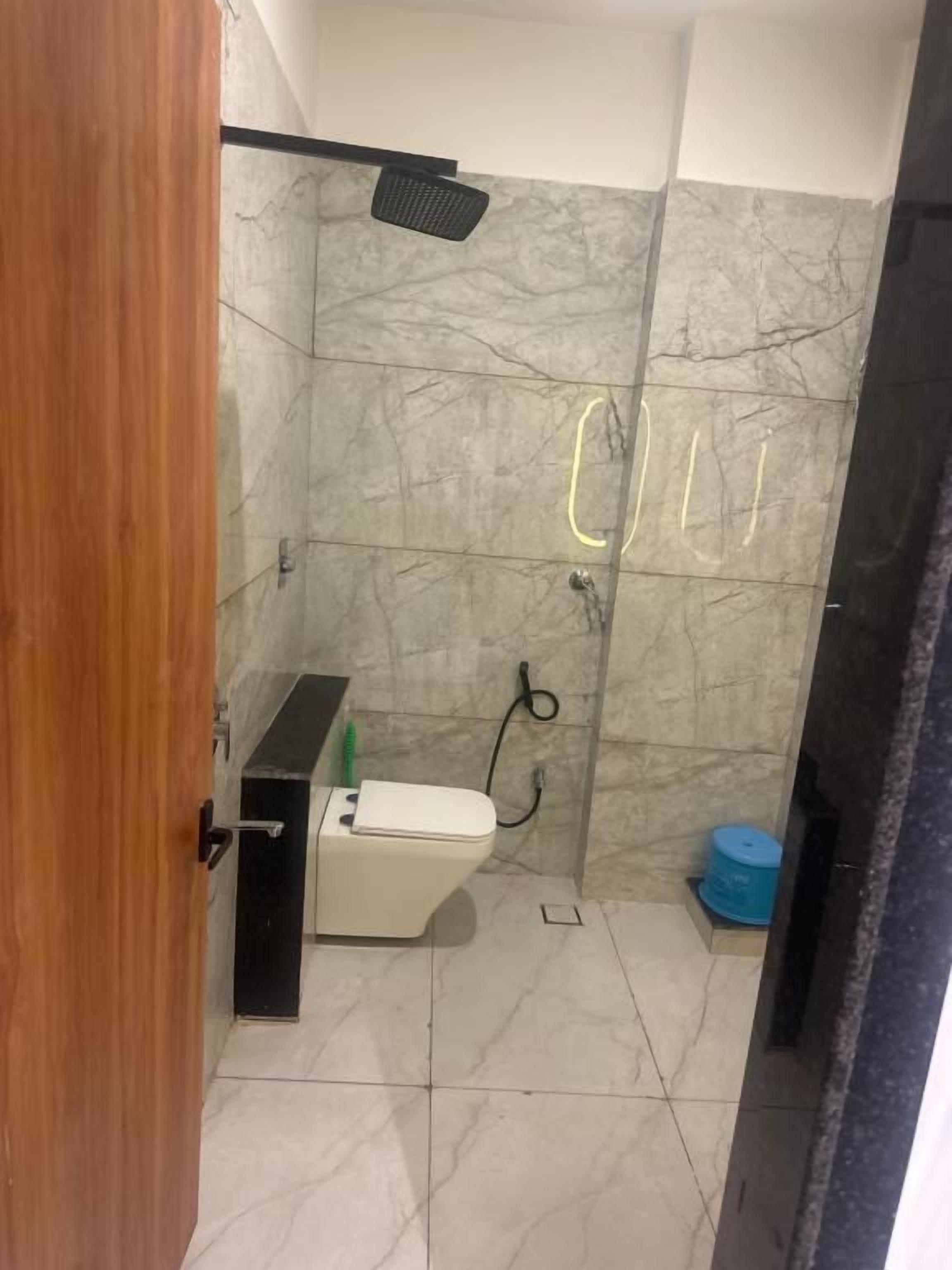 Casa de banho com chuveiro, sanita e lavatório.