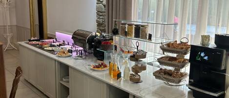 Disposição de buffet com diversos alimentos e uma máquina de café.