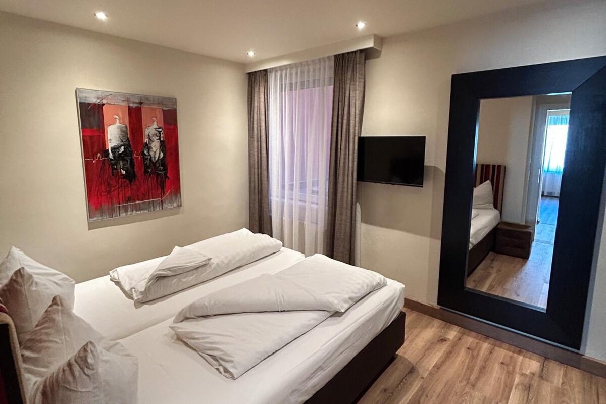 Quarto moderno com uma cama grande, televisão de tela plana e um espelho.