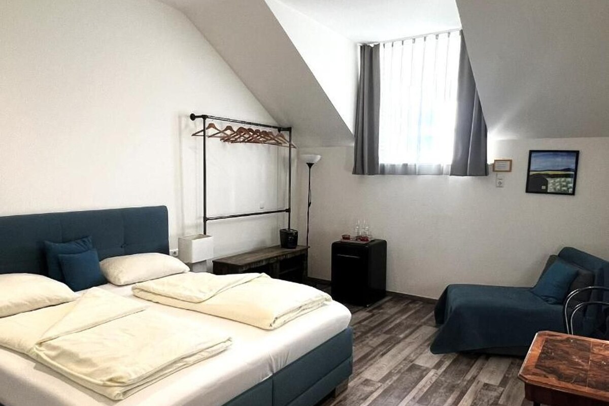 Quarto moderno com uma cama grande, um sofá, uma mesinha e uma escrivaninha.